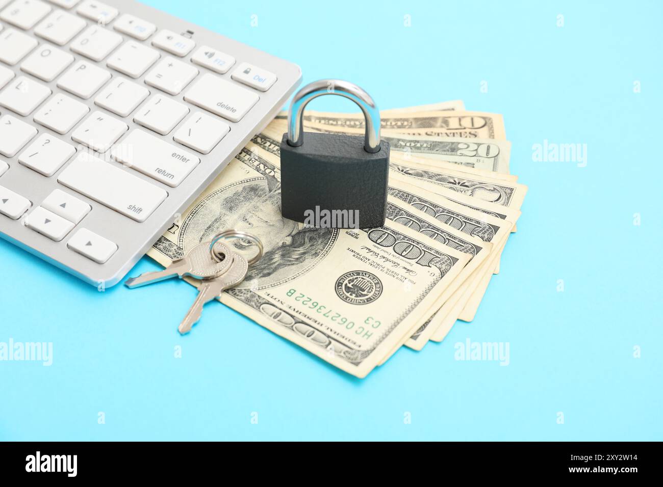 Computer keyboard with dollar banknotes, padlock and keys on blue ...