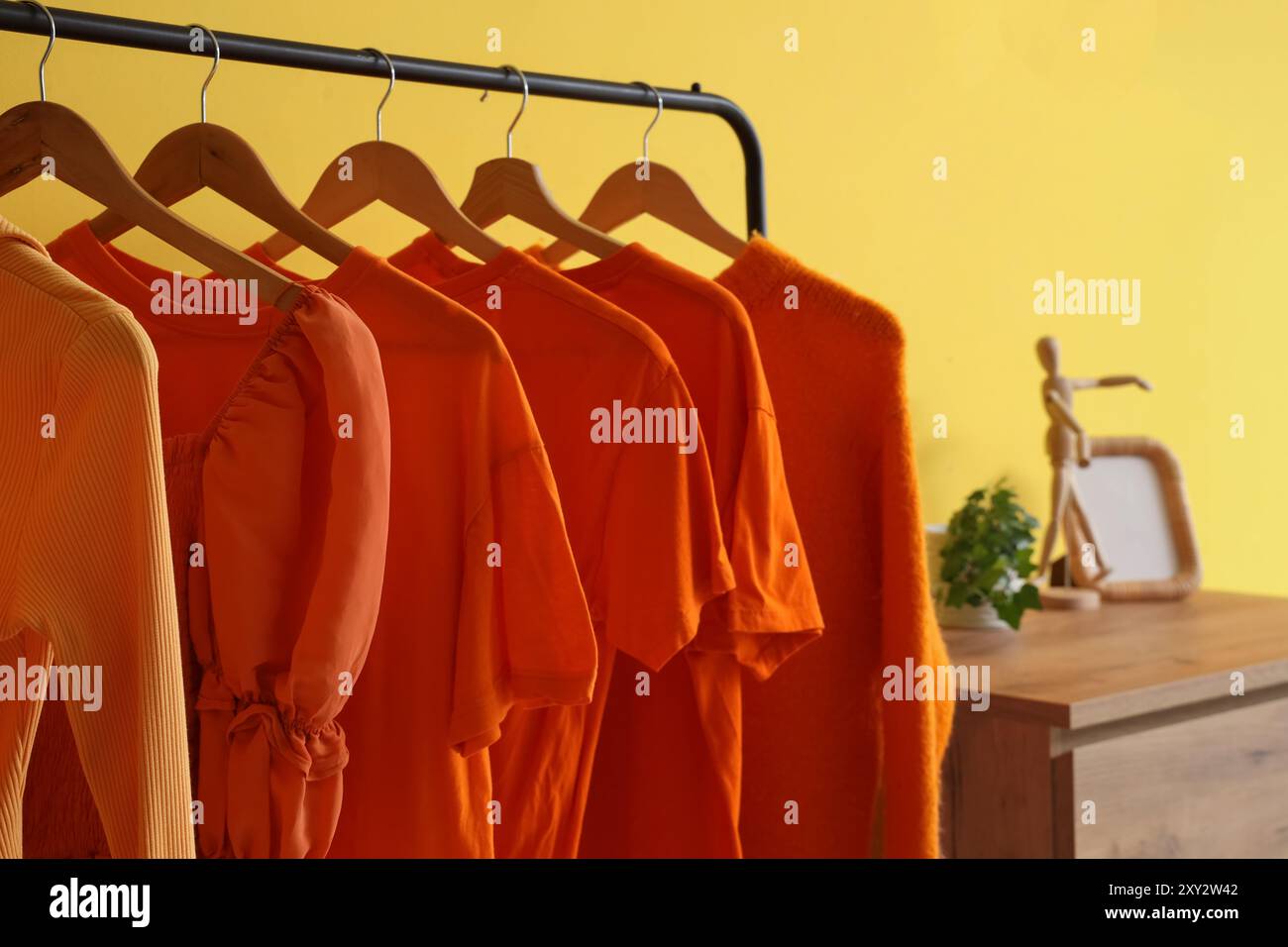 Rack with hanging orange clothes in hallway, closeup Stock Photo - Alamy