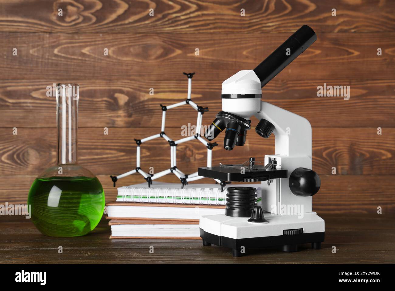 Modern microscope with chemical flask, books and molecular model on ...