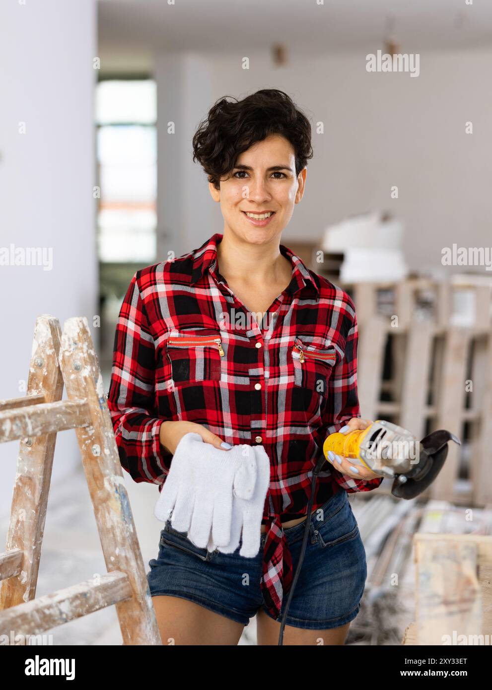 Pretty woman in a plaid shirt and short shorts poses playfully with a ...