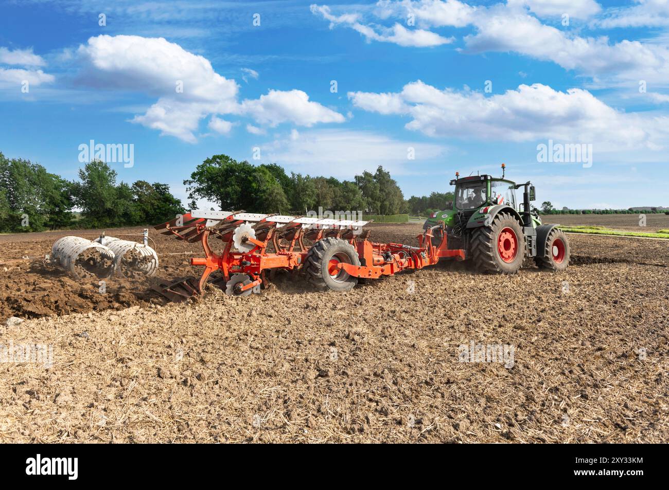 Tractor with 7-blade reversible plough and packer in the field, after ...