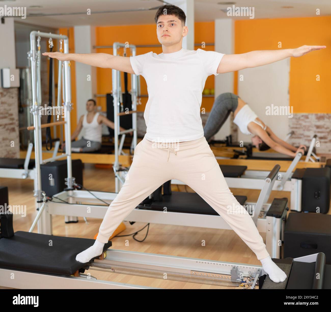 Guy performing pilates exercises on reformer at group workout Stock ...