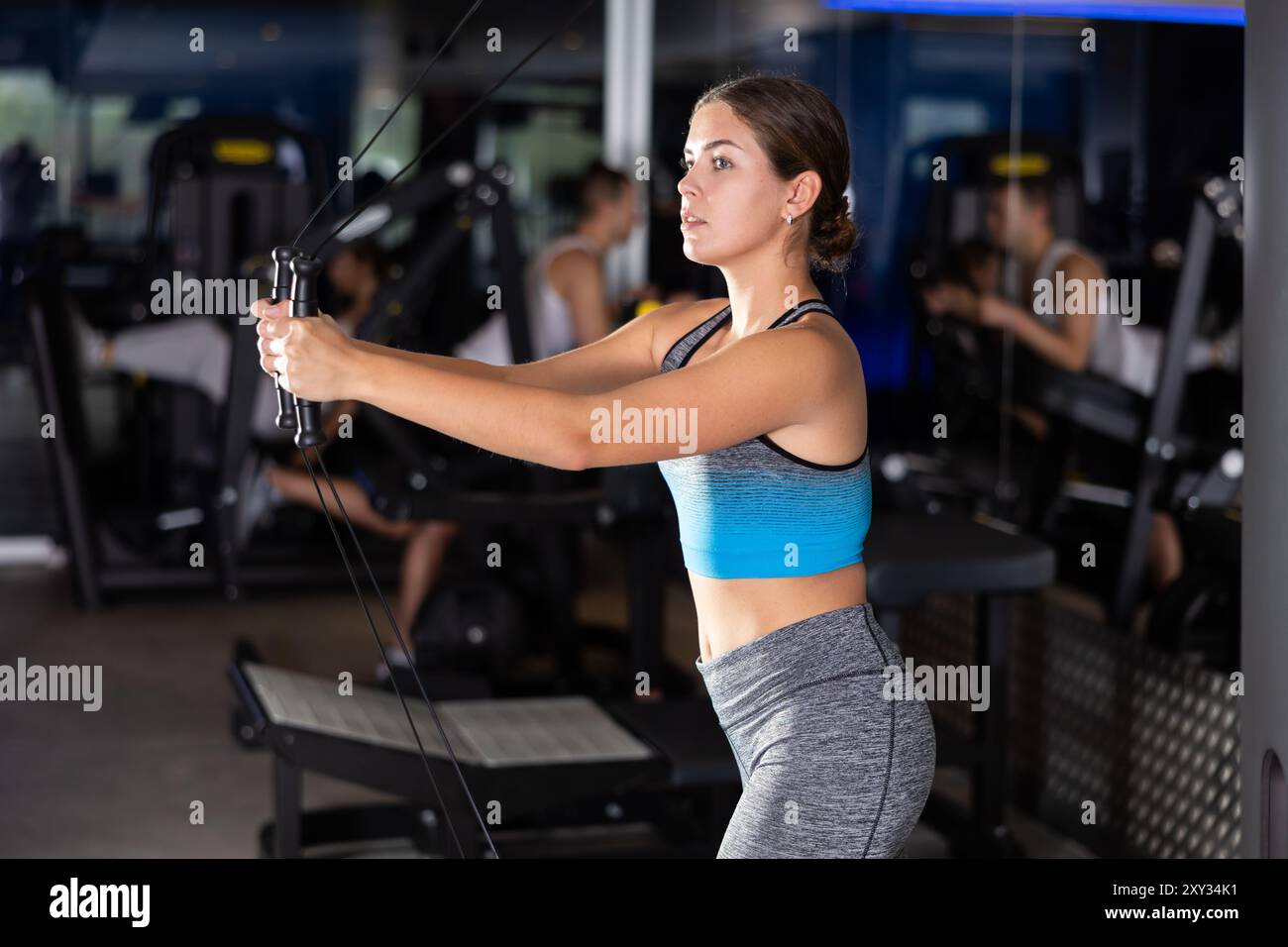 Active athlete young woman during exercises on crossover exercise ...