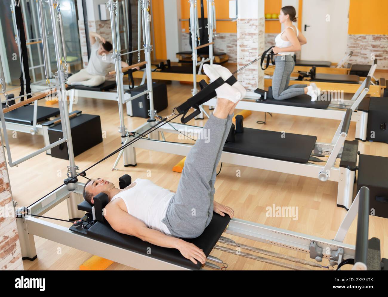 Man works out in gym and performs set of exercises to stretch leg ...