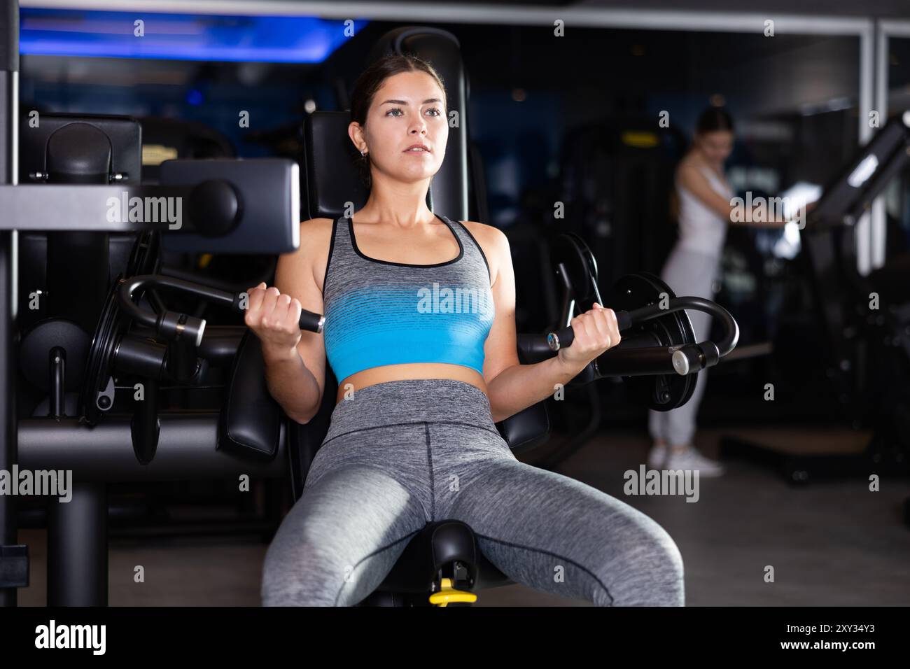 Slender athletic girl work out muscles of arms and shoulders on ...