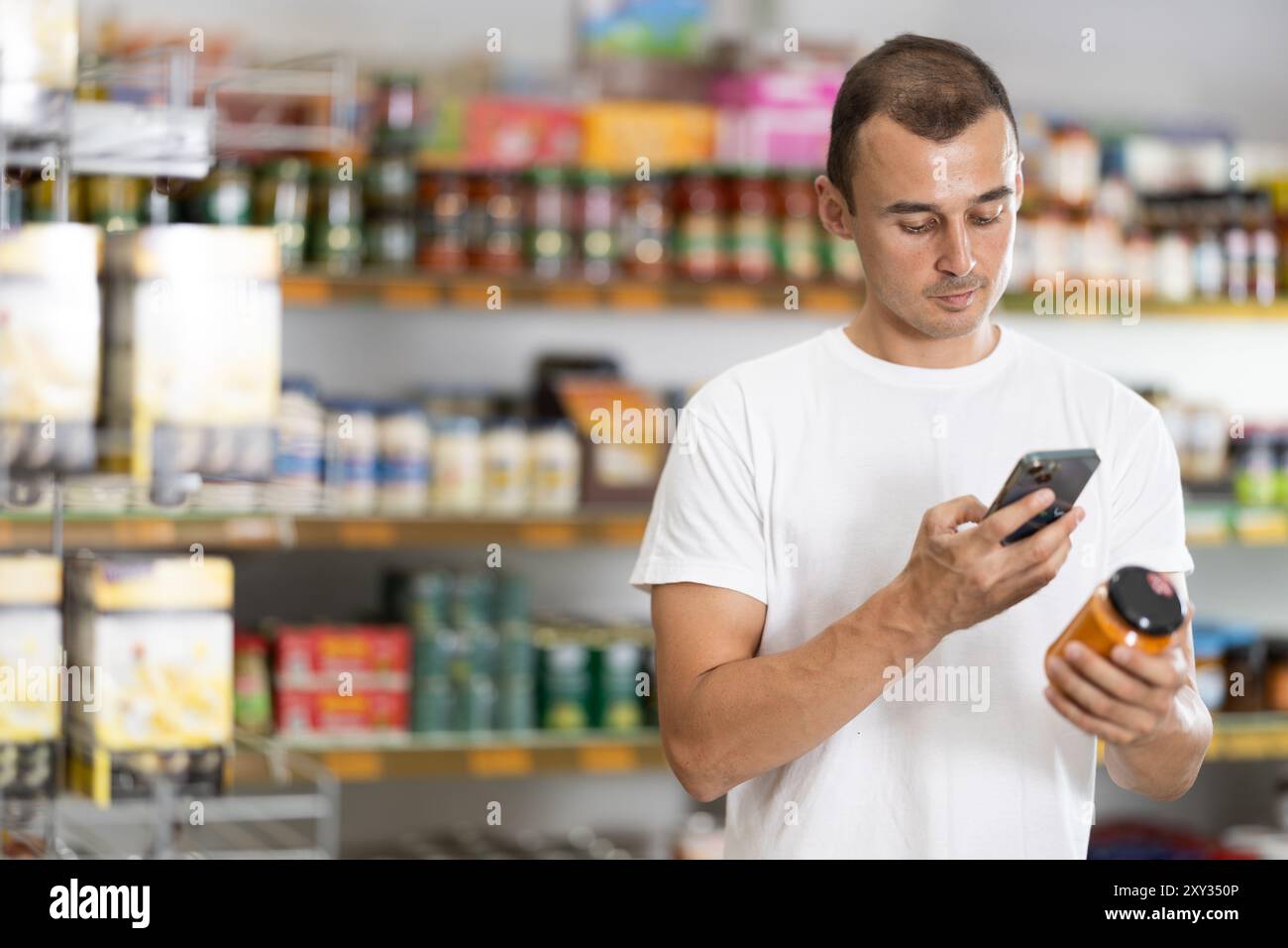 Male shopper scanning barcode or qr code with smartphone on canned food ...