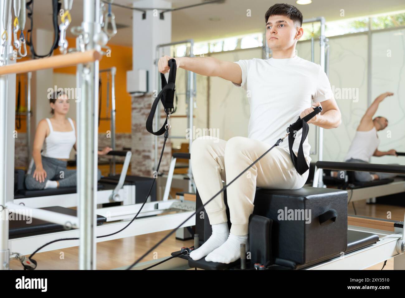 Man in gym with help of rope reformer performs exercises to strengthen ...