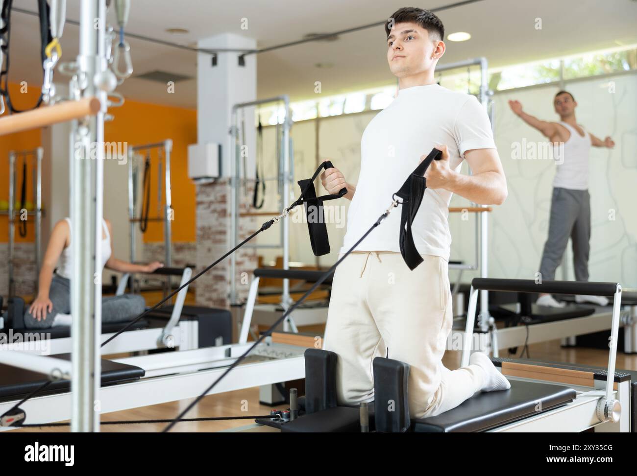 Man in gym with help of rope reformer performs exercises to strengthen ...