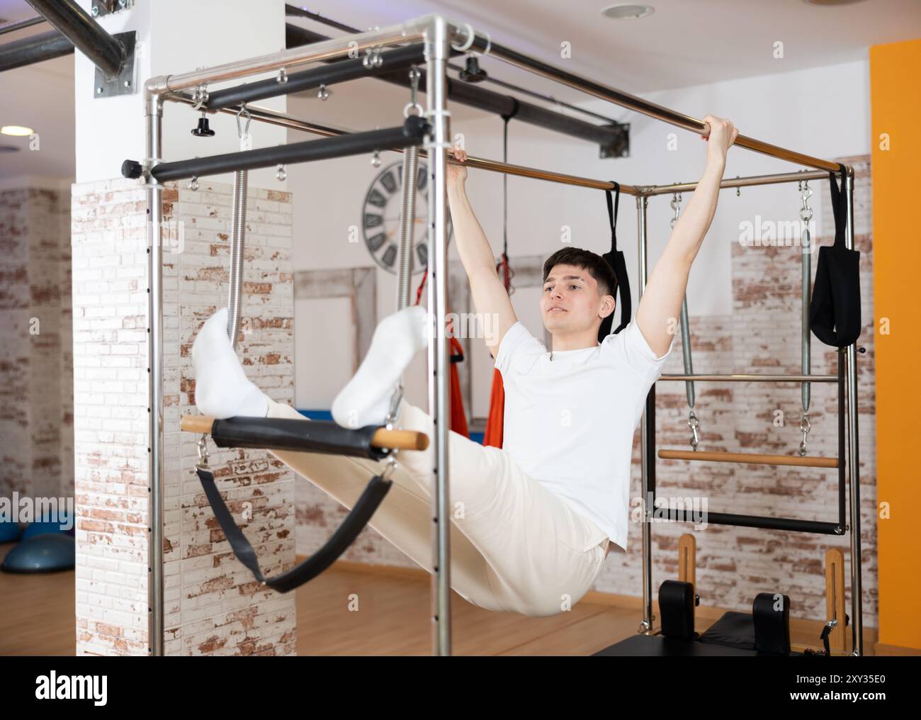 Guy performing hanging exercise on trapeze table in Pilates studio ...
