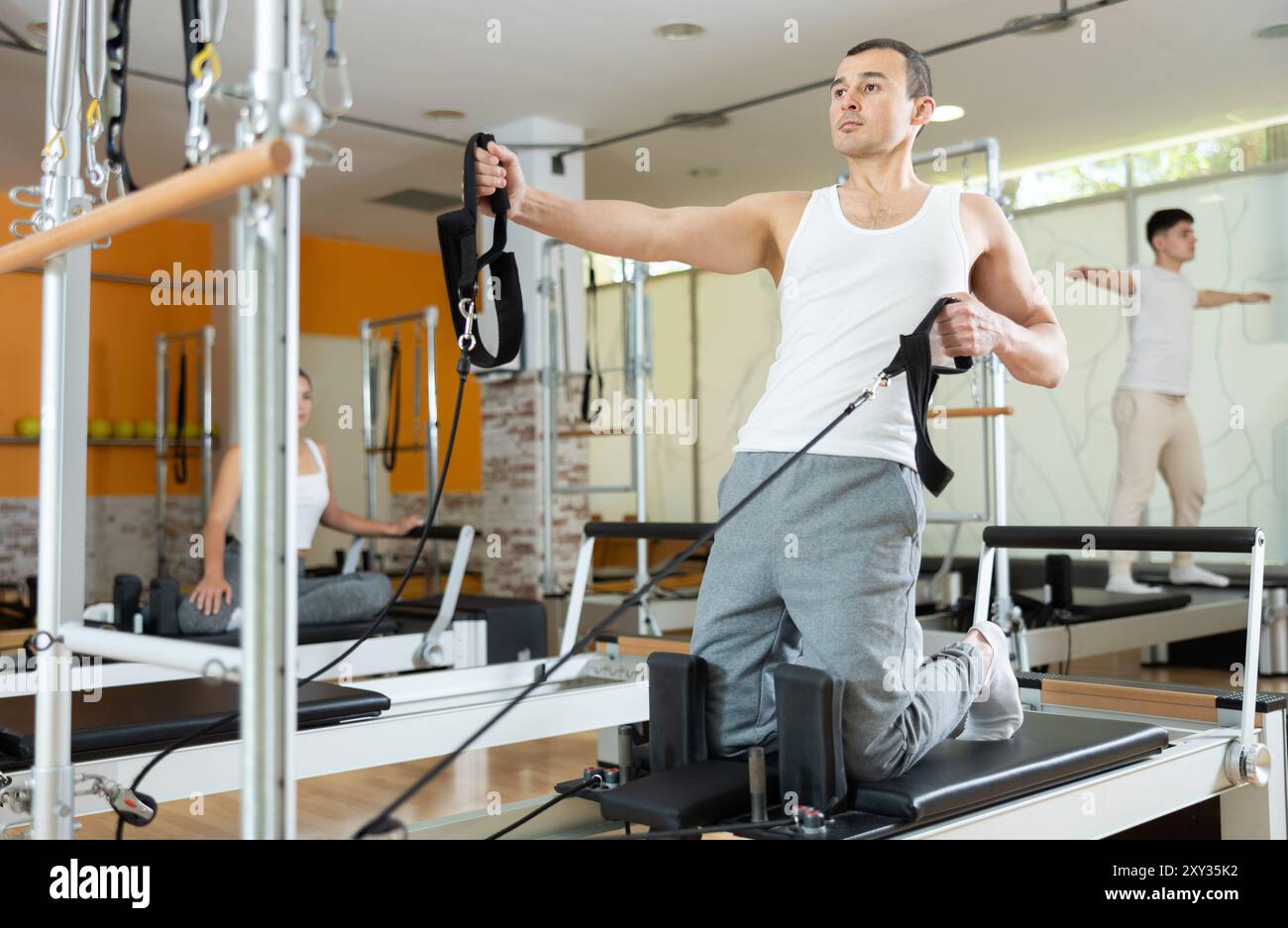 Man in gym with help of rope reformer performs exercises to strengthen ...