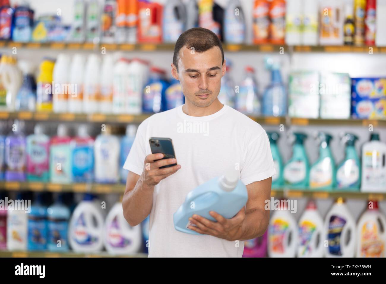 Man examines liquid laundry detergent in supermarket department and ...