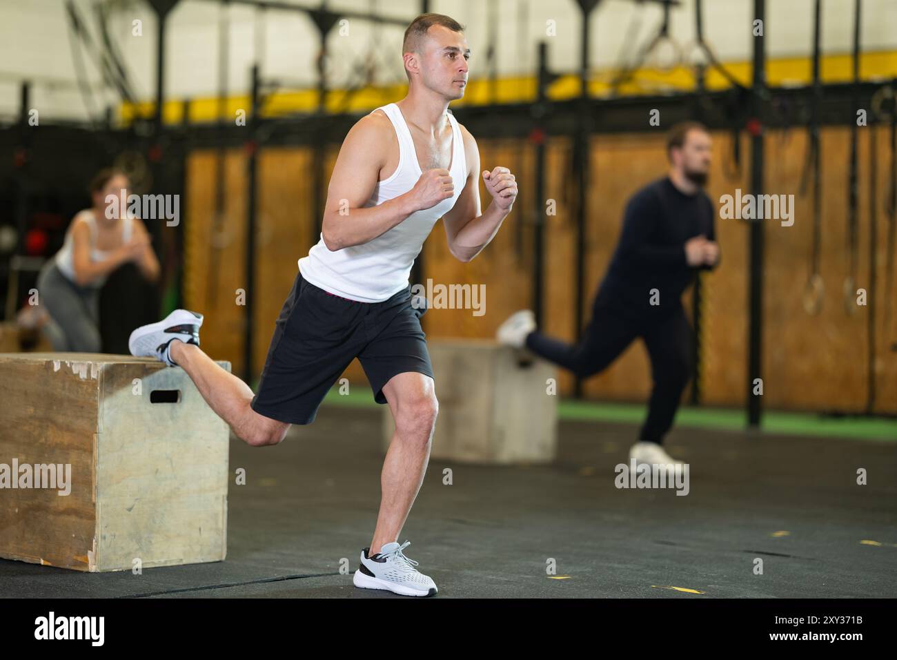 Sportive young guy practicing one leg squats with box during crossfit ...