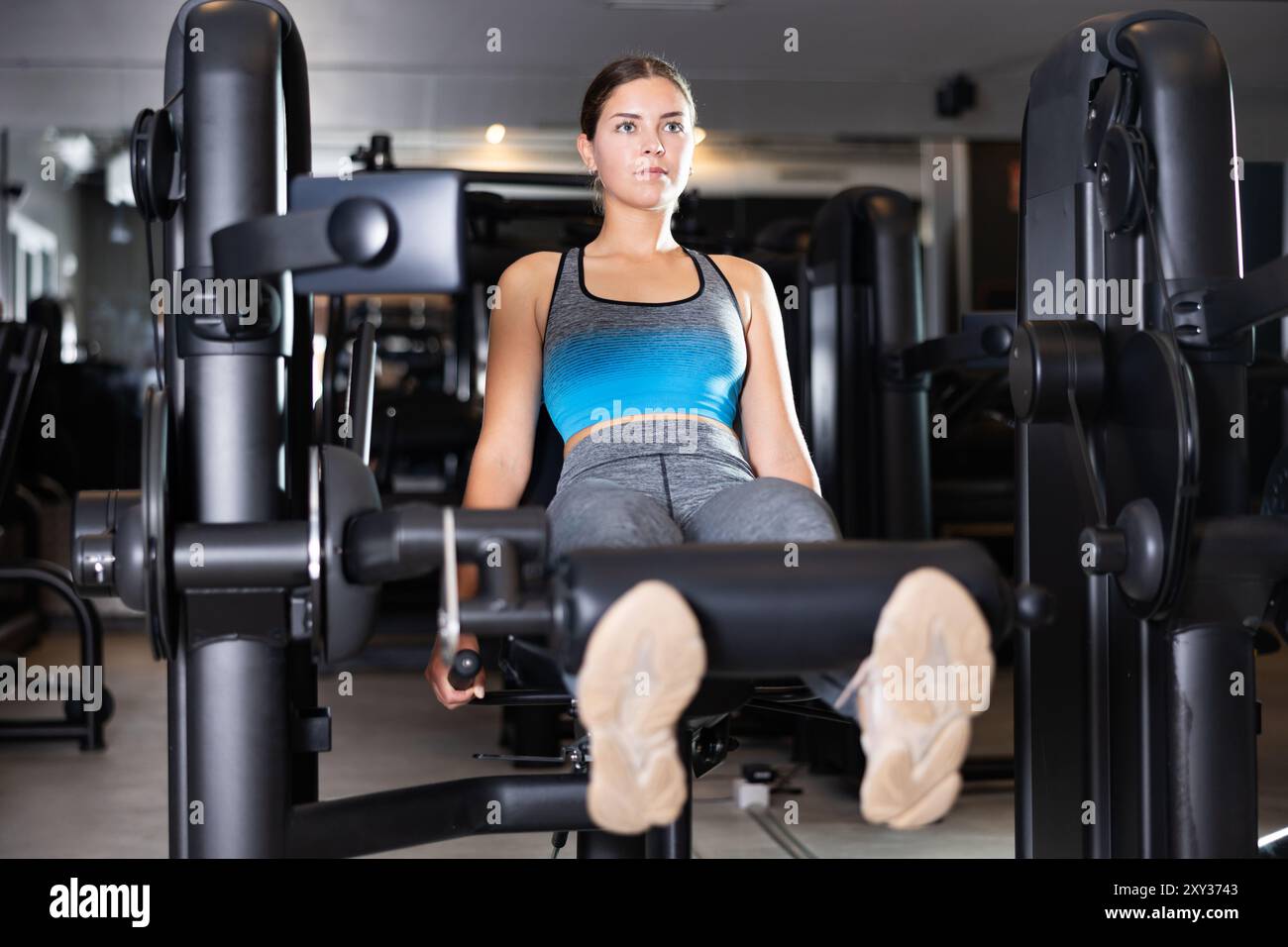 Sportive young girl training on leg extension machine in gym Stock ...