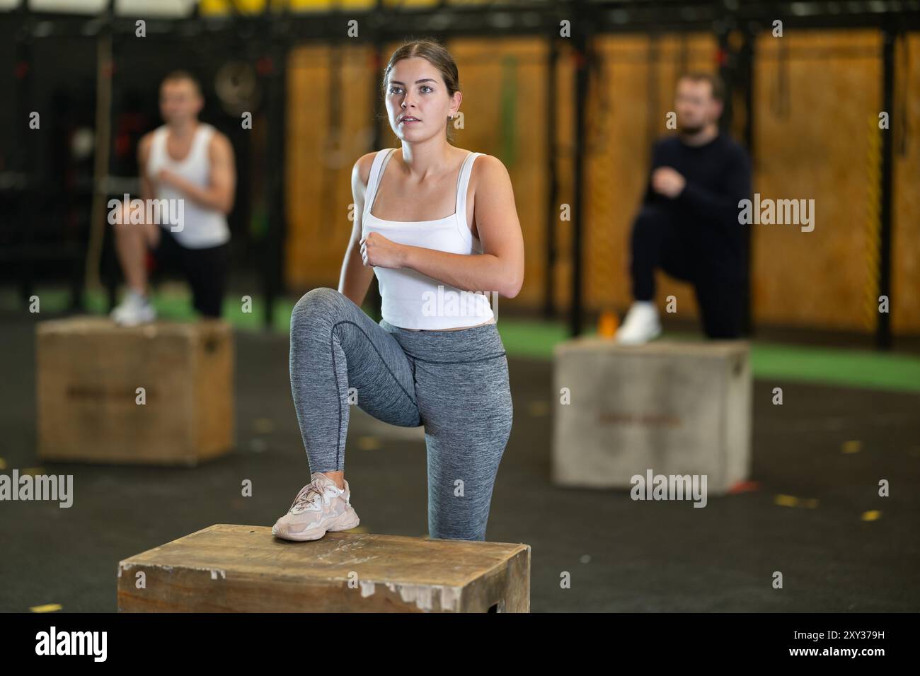 Sportive young girl doing step-up exercises with box during crossfit ...