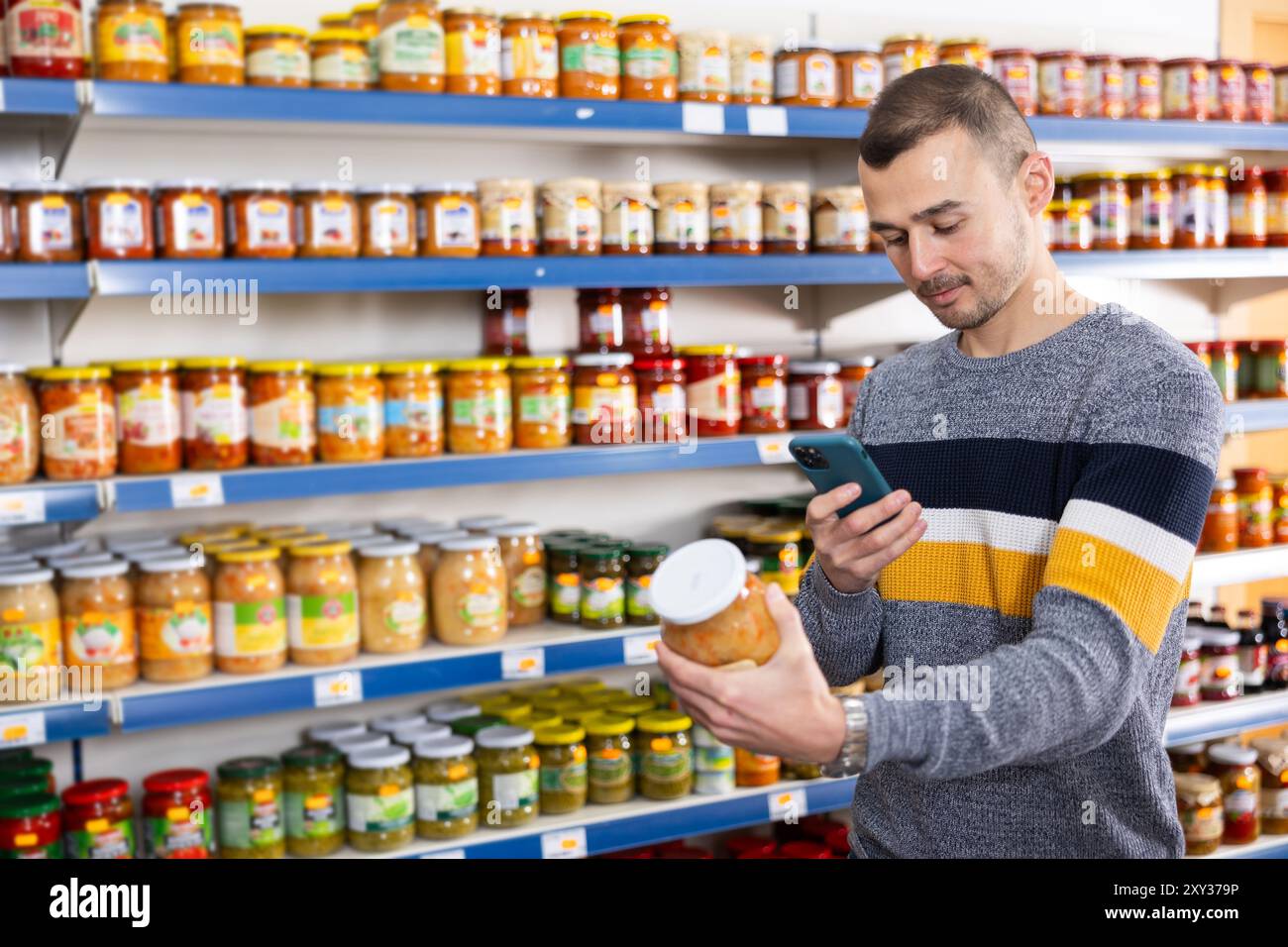 In Russian goods store, man choose jar of pickled fermented cabbage and ...