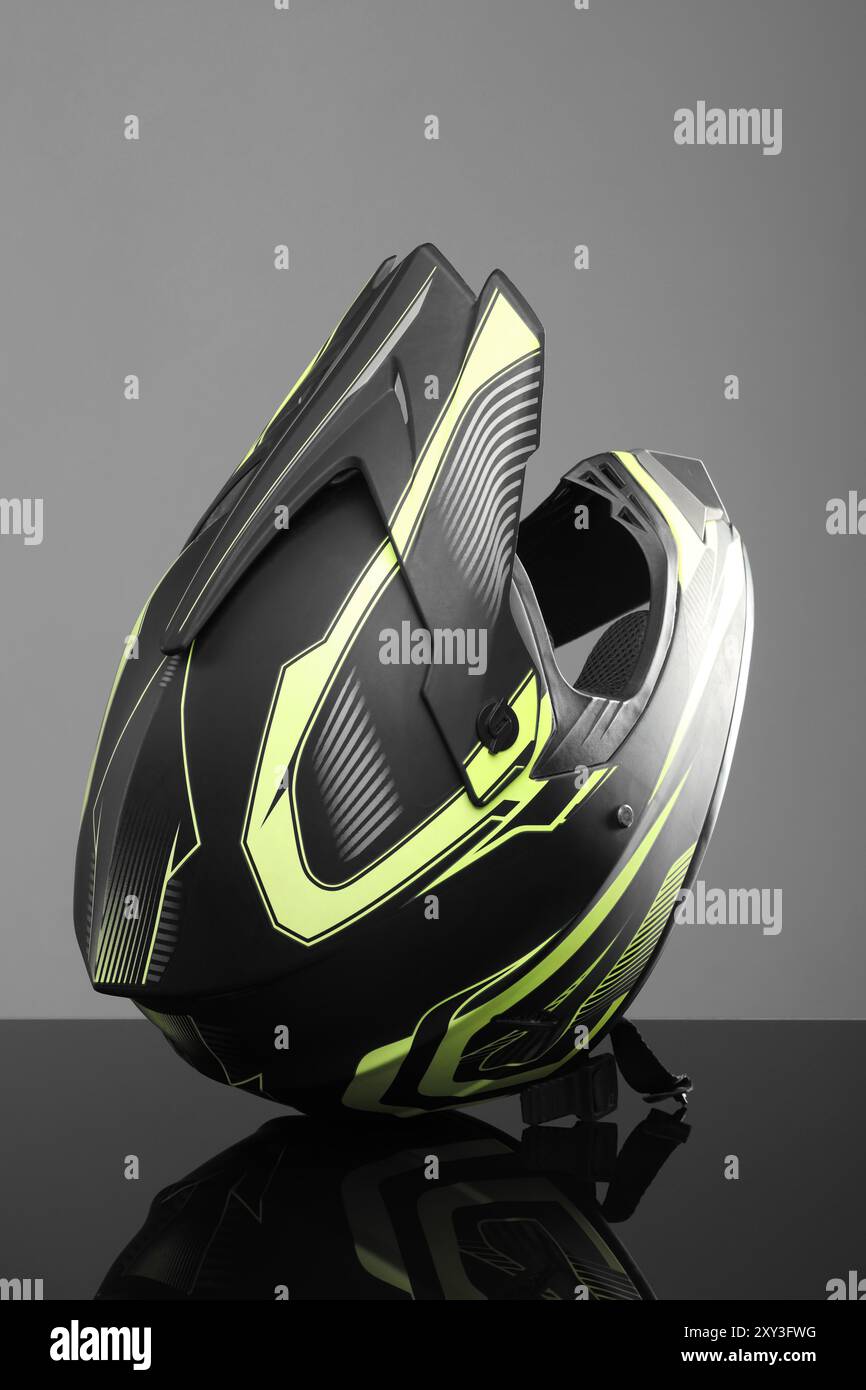 Modern motorcycle helmet with visor on mirror surface against light ...