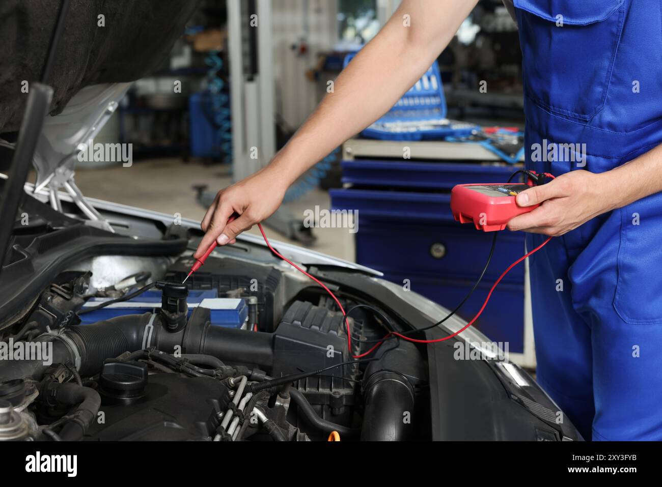 Auto mechanic with multimeter doing diagnostic at automobile repair ...