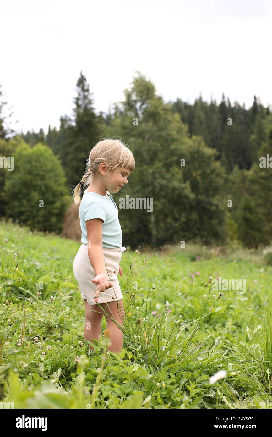 Cute little girl walking at green meadow. Enjoying beautiful nature ...