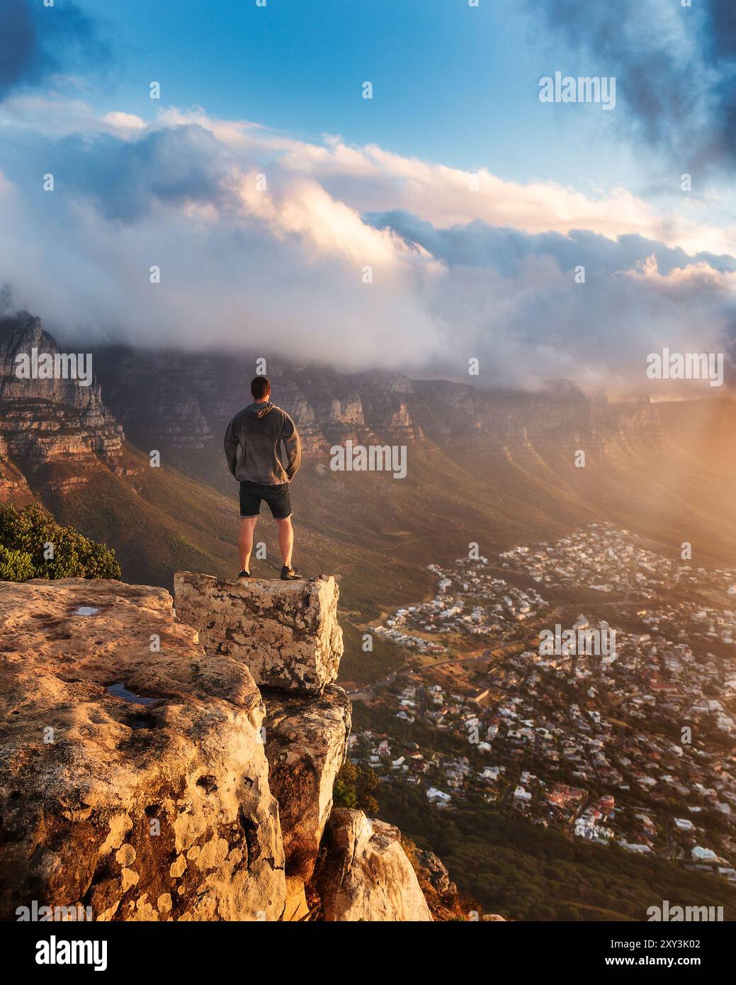 Young man standing on the top of the rock. Success, achieved goal ...
