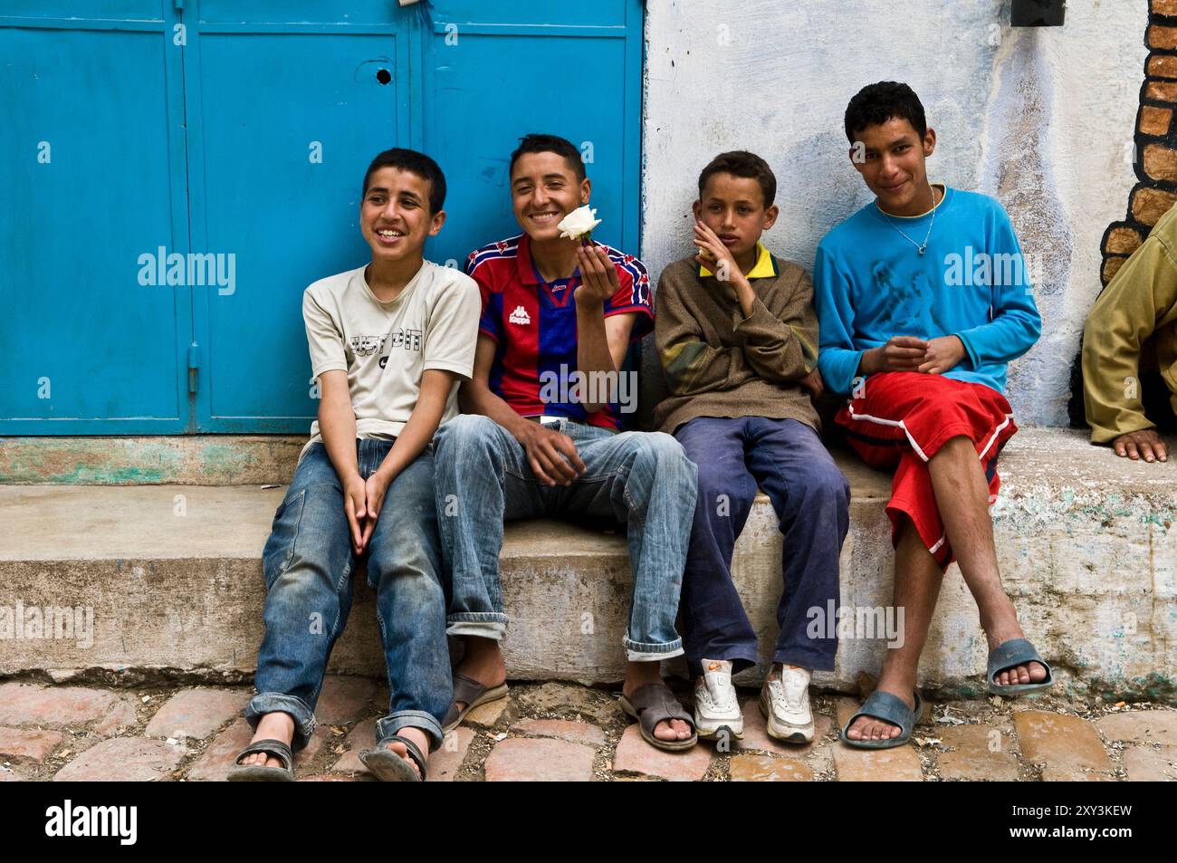 Joyful Moroccan children sitting by a shop in a small town in the ...
