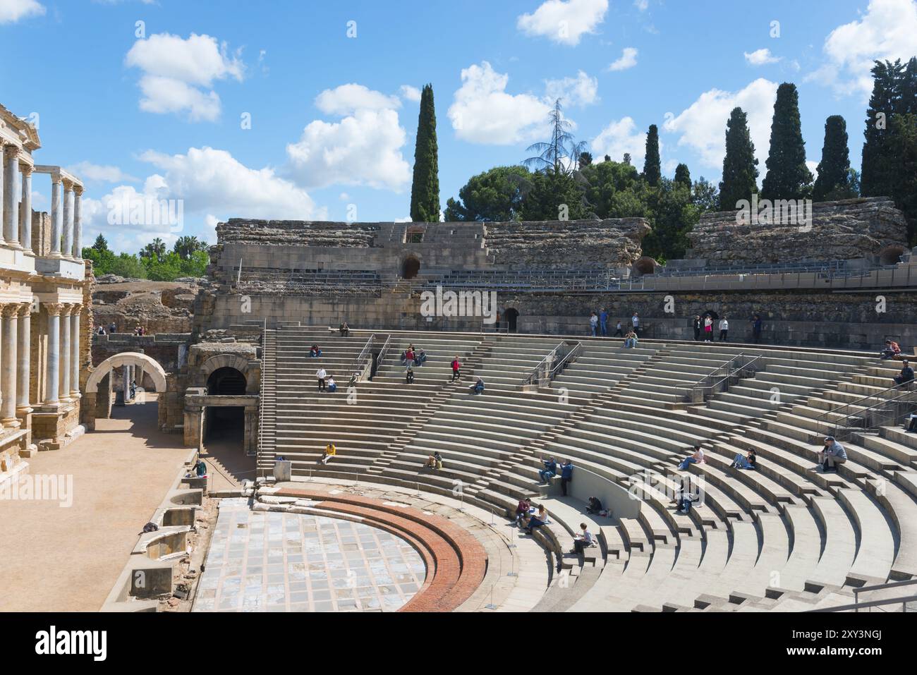 An ancient amphitheatre with stone seats under a blue sky with clouds ...