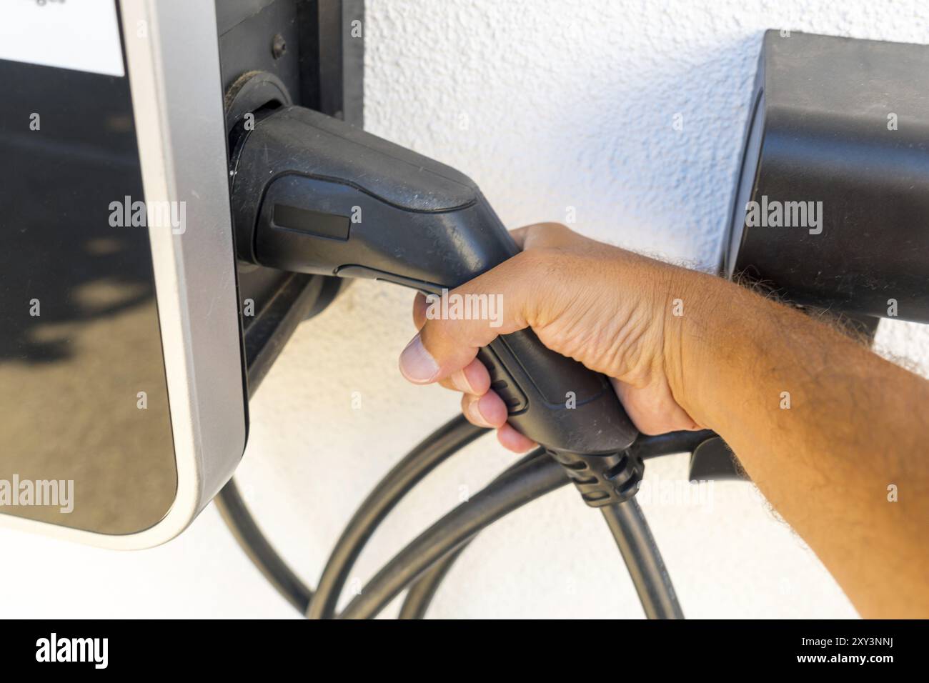 A person is plugging in a car to a charging station. Concept of ...