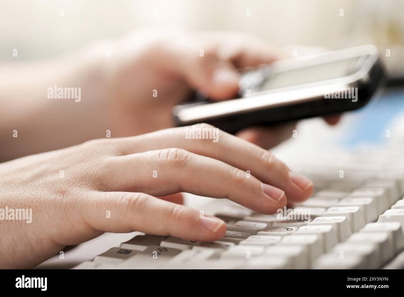 Hand holding mobile phone typing computer keyboard Stock Photo - Alamy