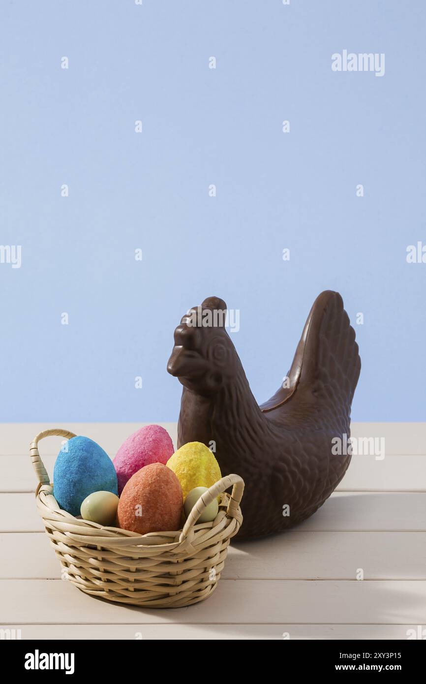 Easter chocolate chicken and colored eggs in a small basket over a ...
