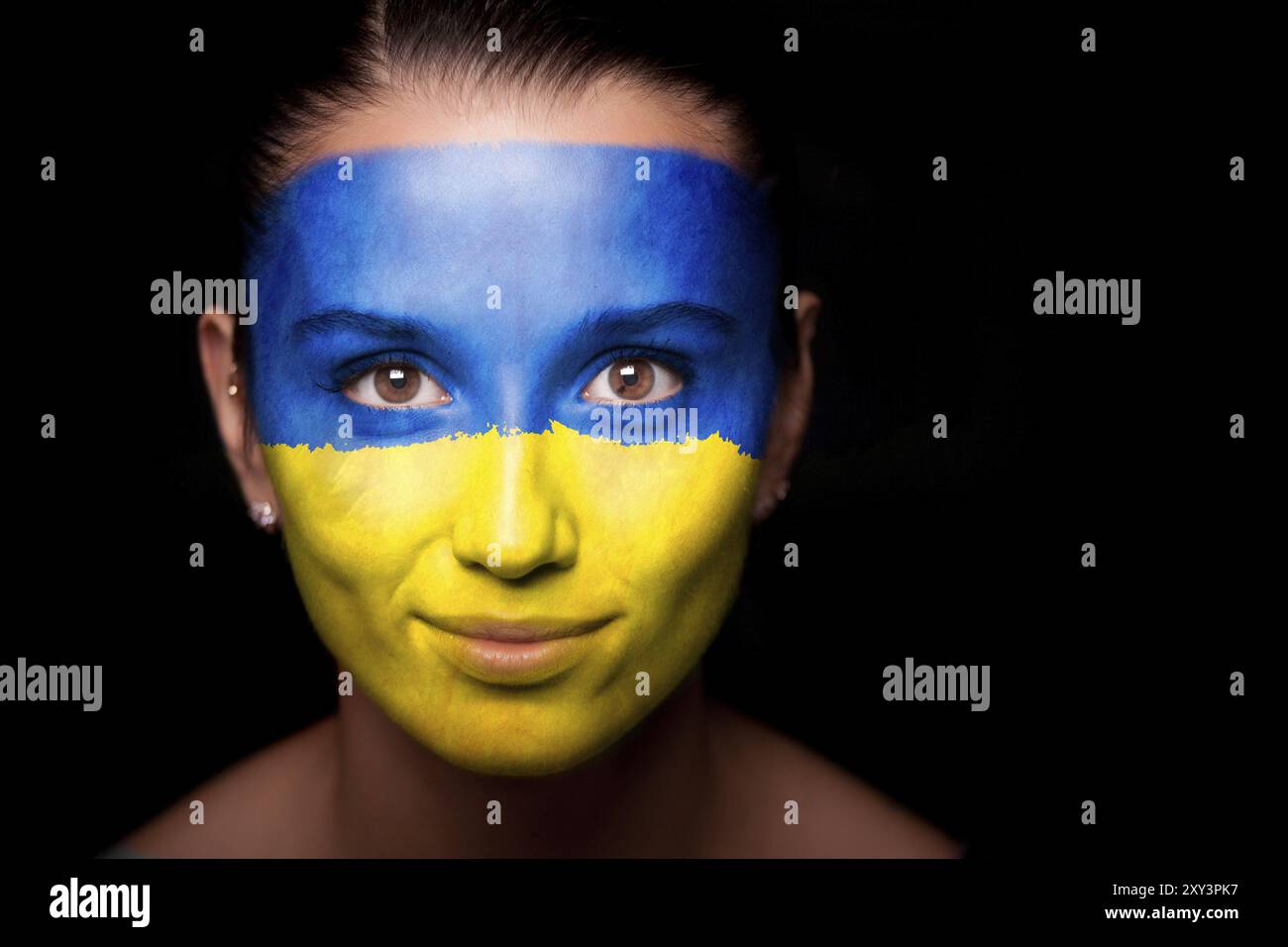 Portrait of a woman with the flag of the Ukraine painted on her face ...