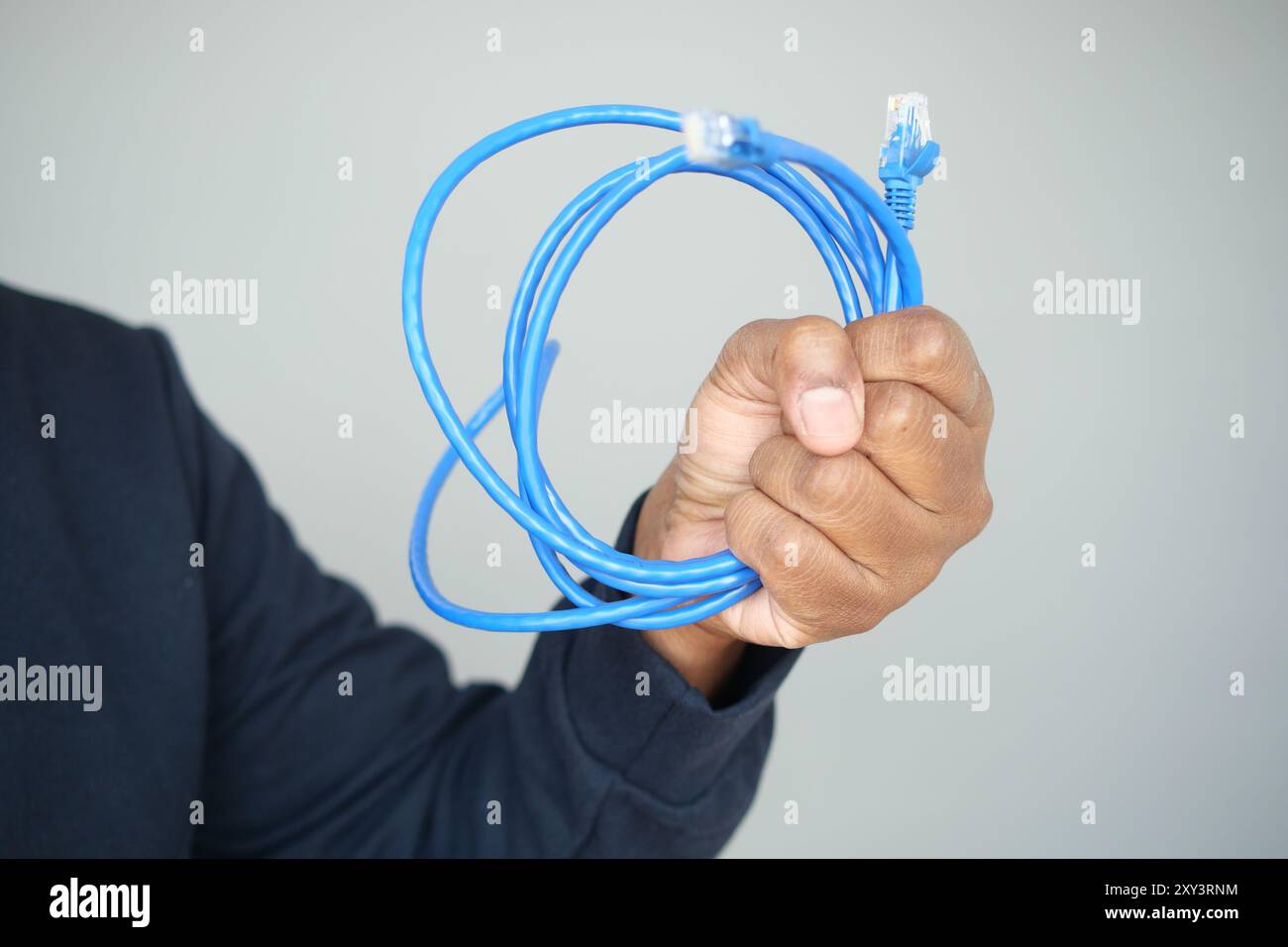 A closeup of hands holding a coiled blue Ethernet cable for a network ...