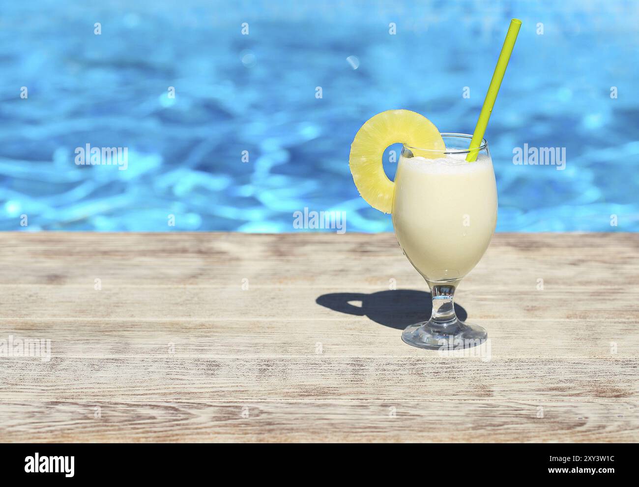 Glass of pinacolada cocktail standing on the swimming pool ledge in an ...