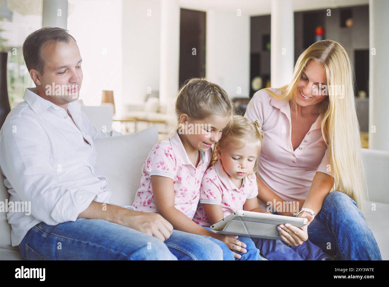 Attractive happy family of mother, father and daughters sitting on a ...