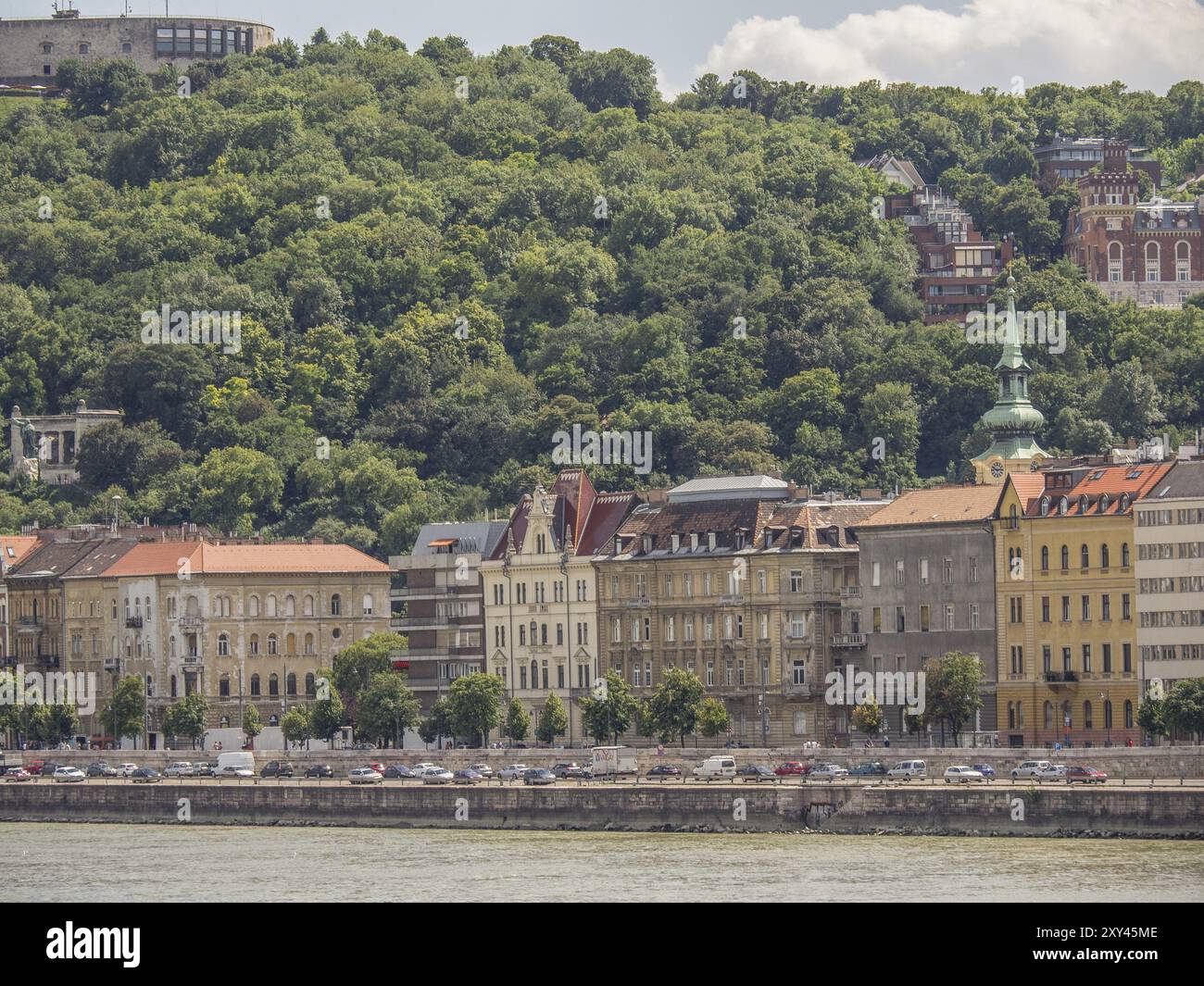Row of historic buildings along a river, surrounded by lush greenery on ...