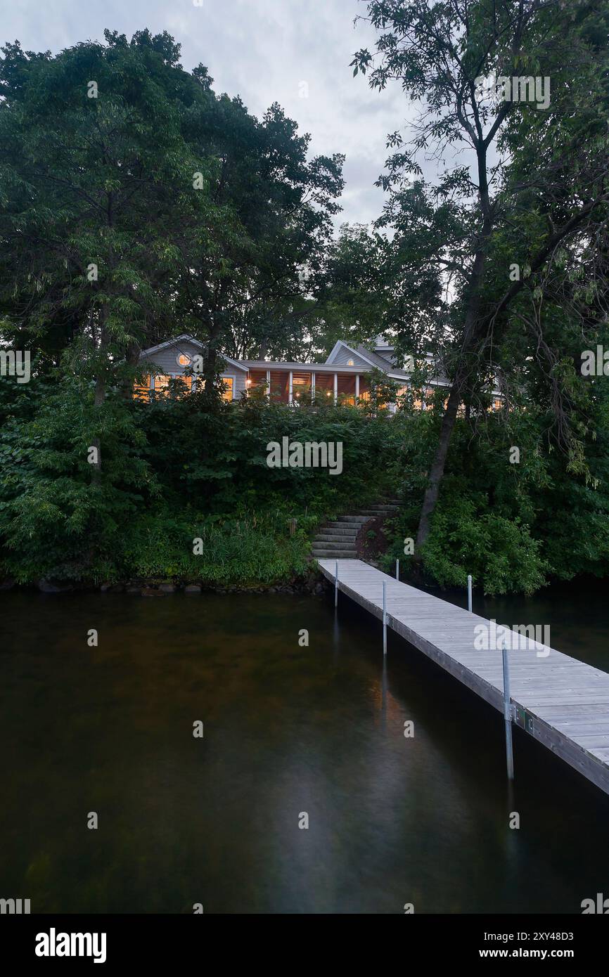 Cottage lit up at night sits among trees on lake Stock Photo - Alamy