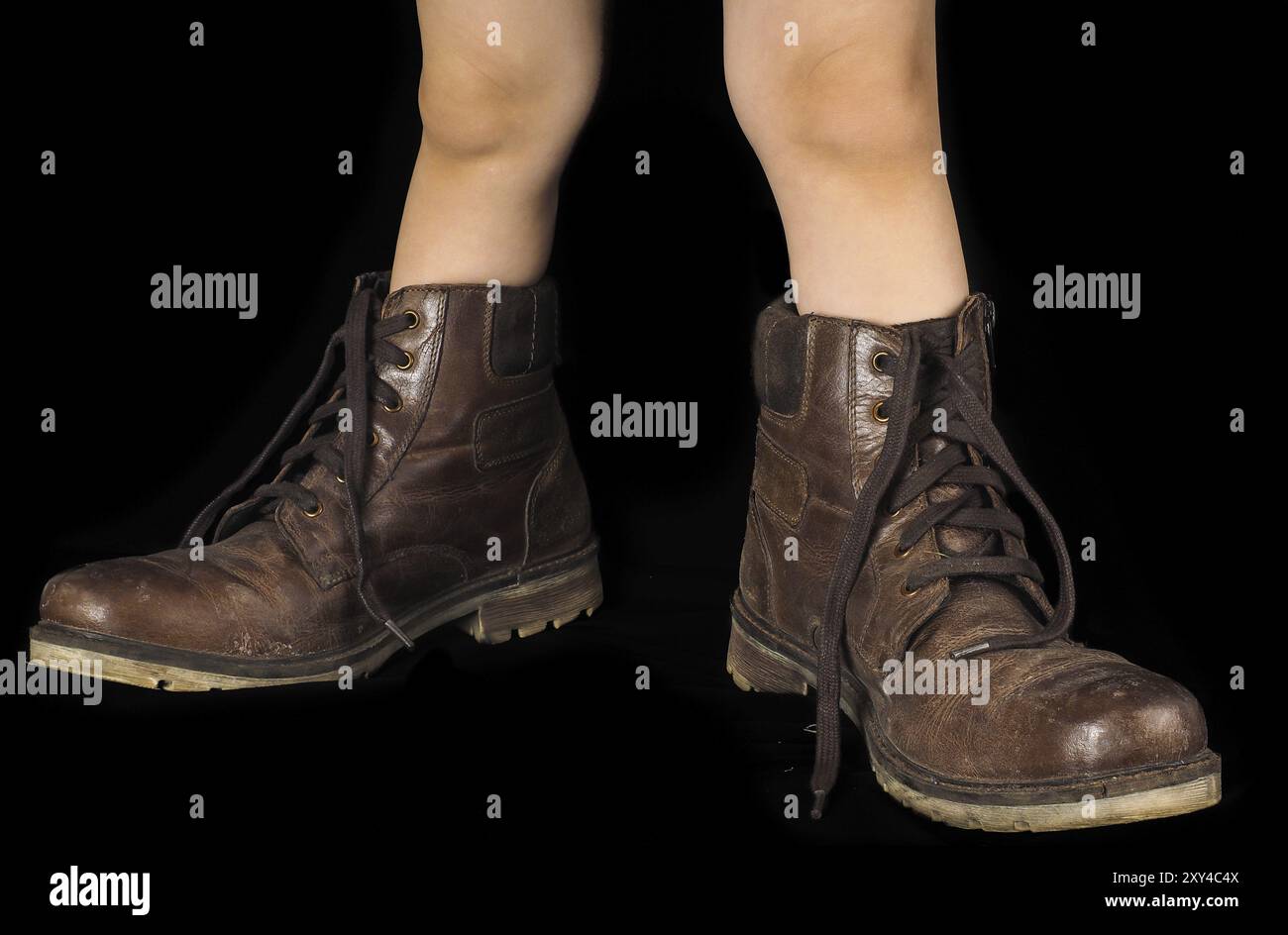 Kid wearing a pair of too big untied and unpolished brown leather boots ...