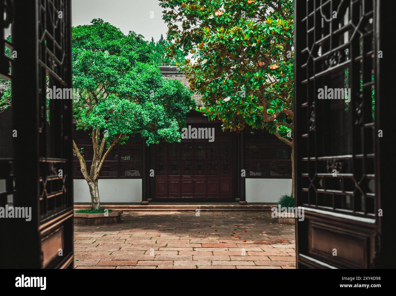 A view through an ornate wooden door into a serene courtyard with a ...