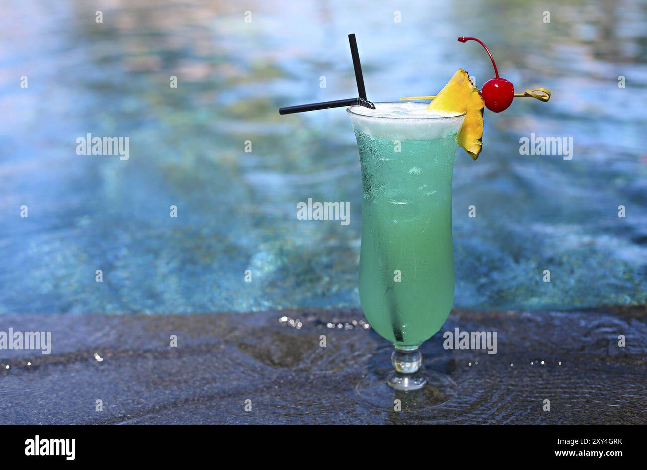 Glass with a bright blue lagoon cocktail by the pool. Luxury resort on ...