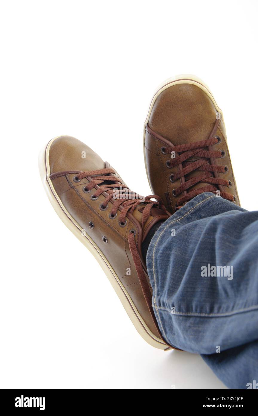 Male legs in brown shoes sneakers and jeans lying down on the grownd ...