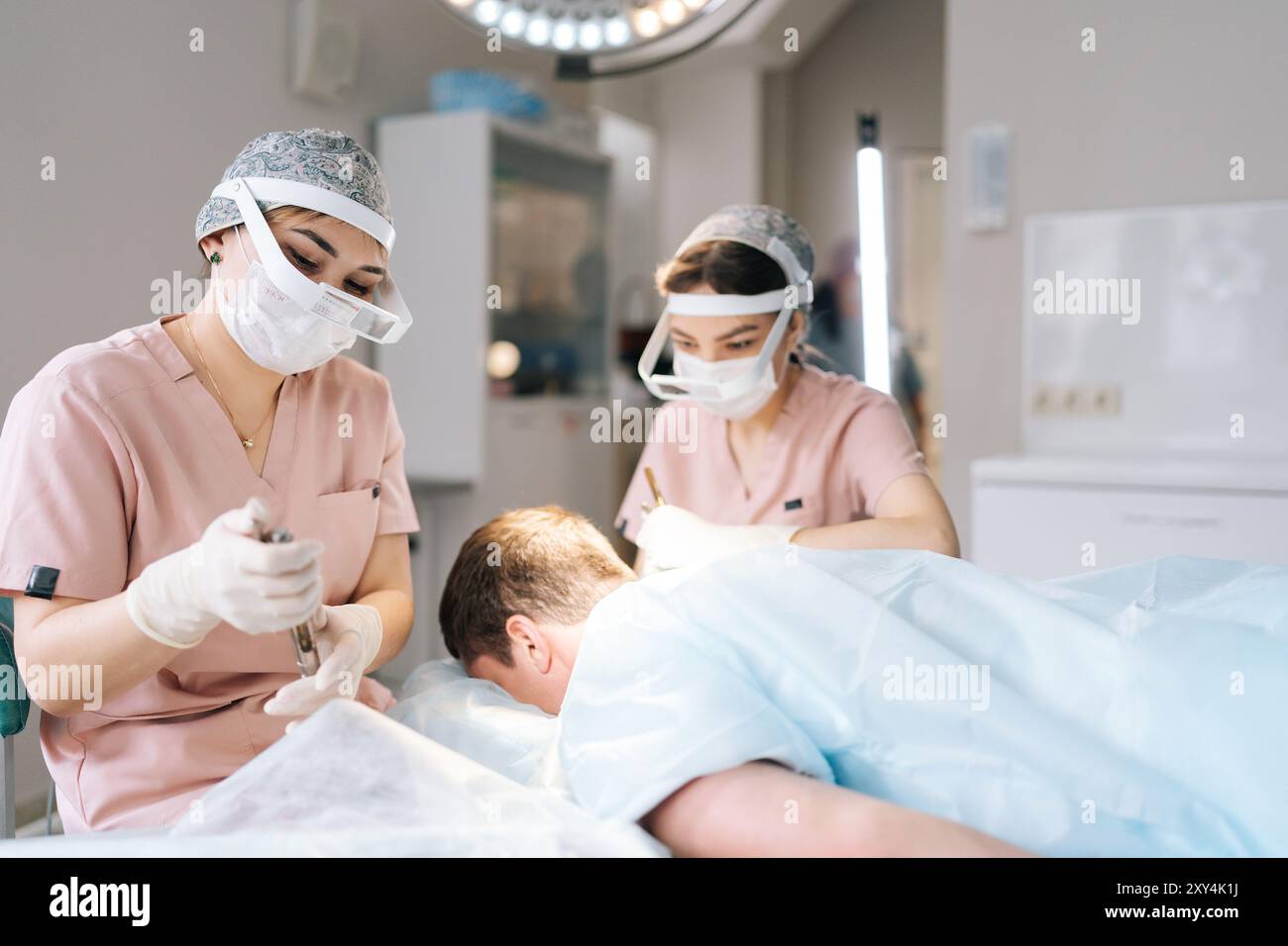 Two female trichologist performing local needle-free anesthesia to back ...