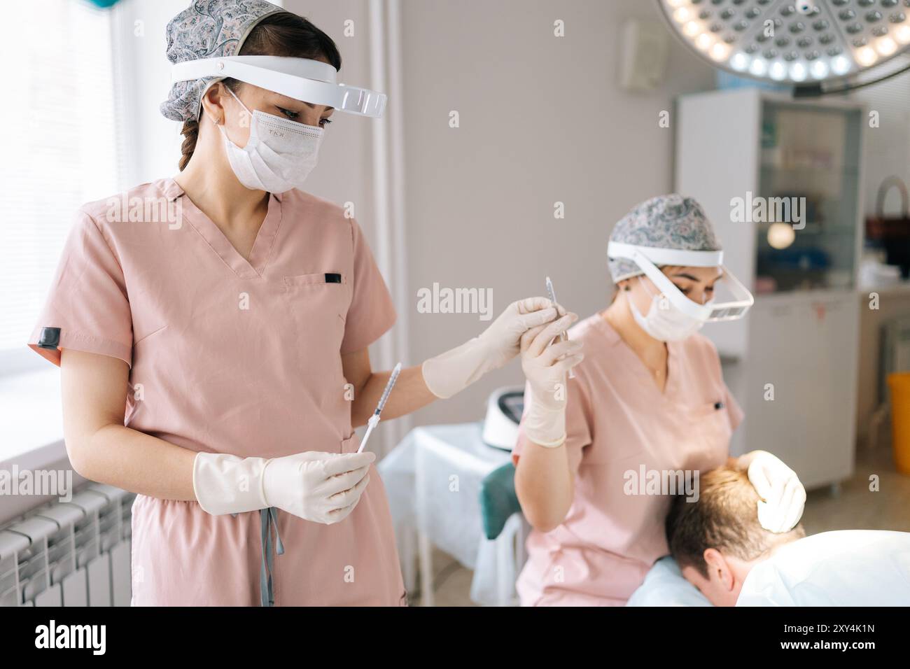 Two female trichologist performing local anesthesia to back of head in ...