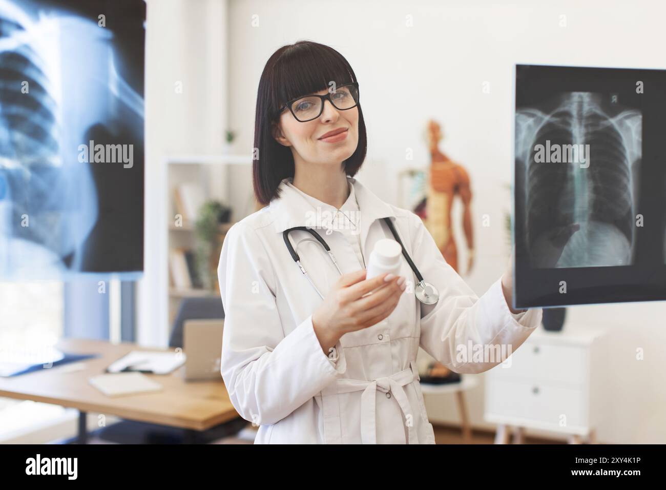Female doctor examining x-ray and holding medication bottle Stock Photo ...