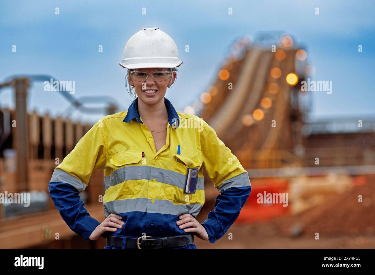 Woman mining company employee with iron ore loader in the background at ...
