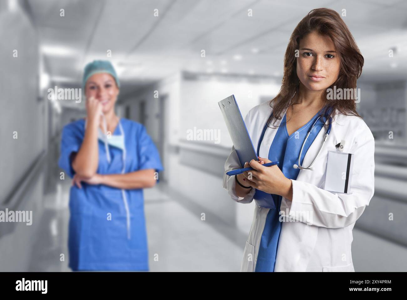 Female doctor writing in a notepad inside an hospital. Another female ...