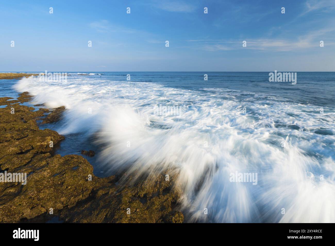 Motion blurred waves crash over the rocks of the rocky coastline of ...