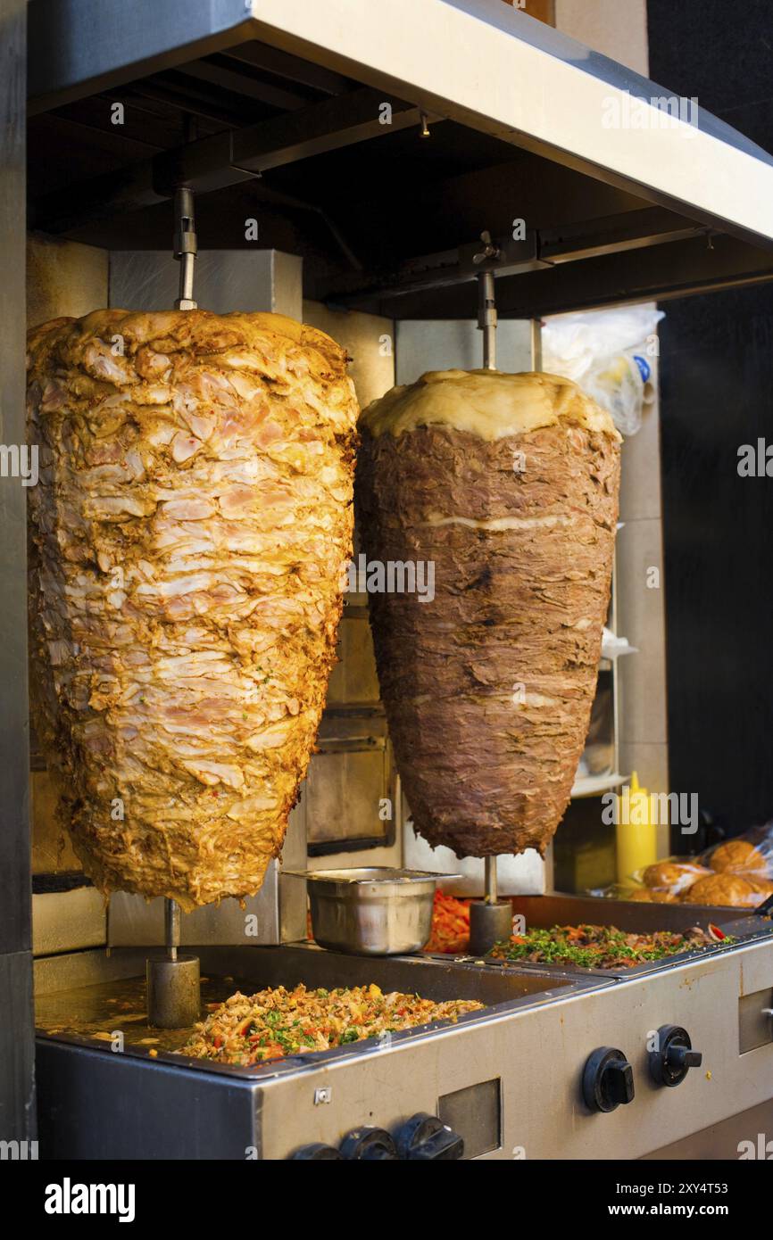 A pair of rotating skewered chicken and lamb meat grilled and ready to ...