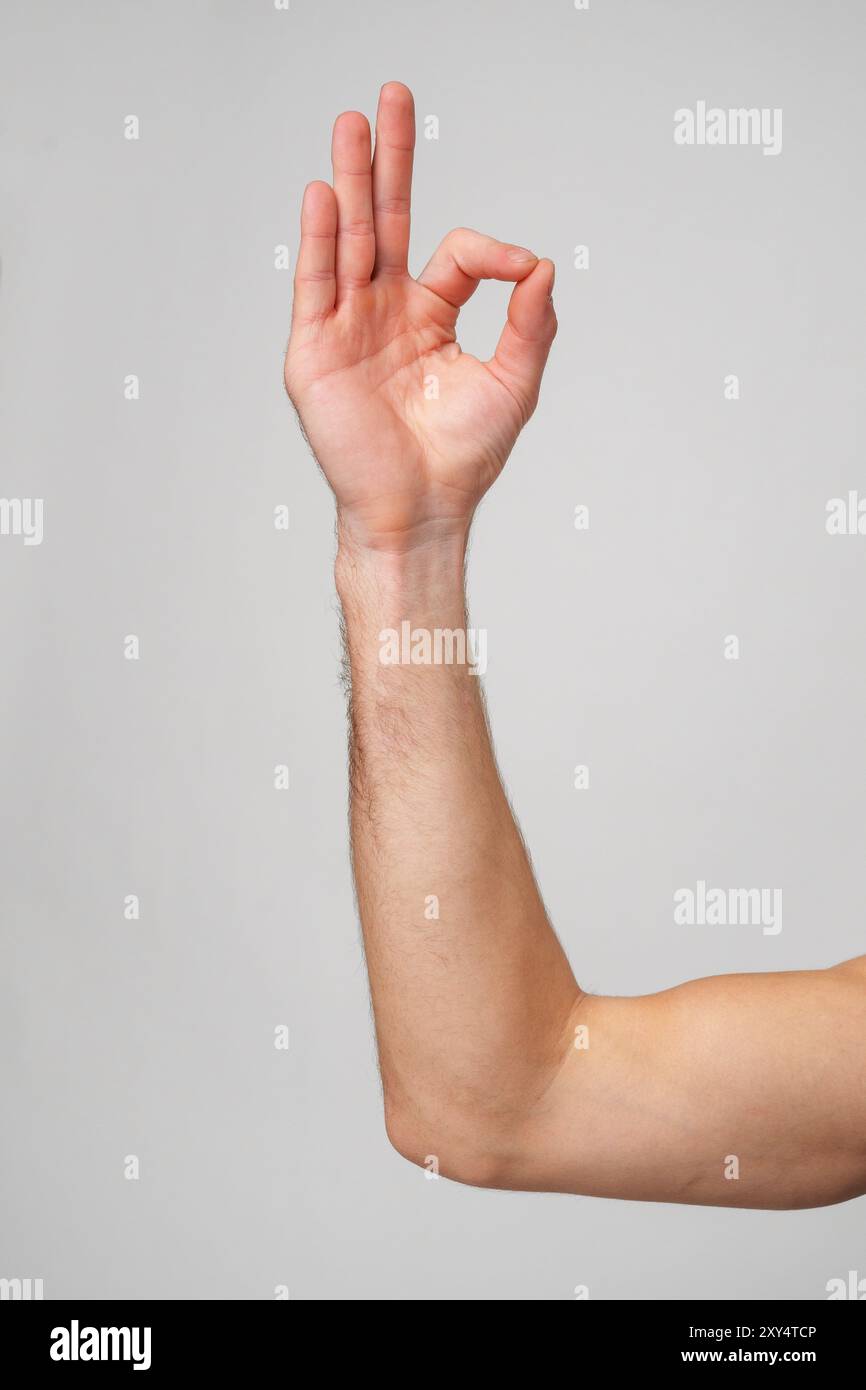 Mans Hand Showing Sign against gray background Stock Photo - Alamy