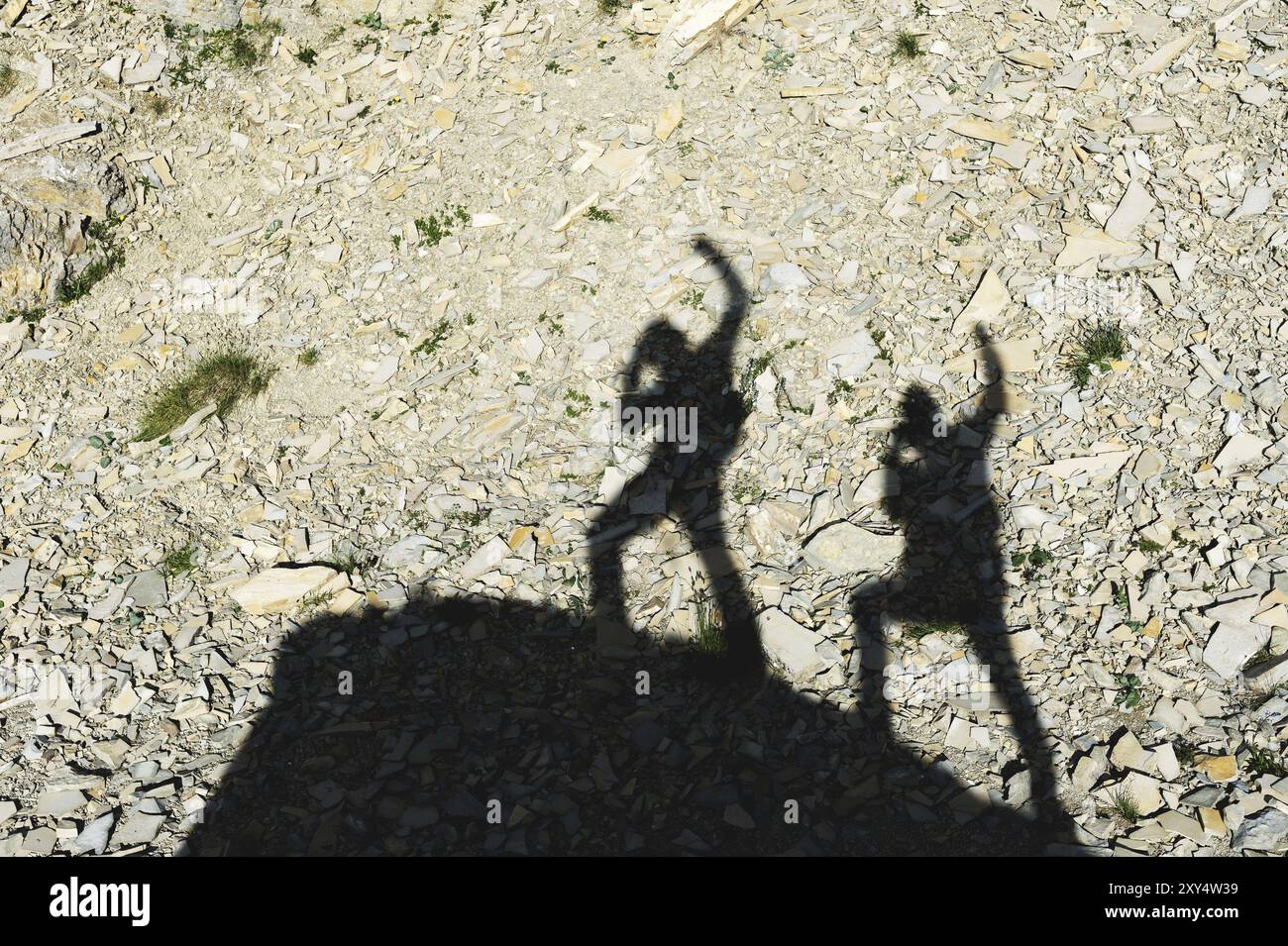 Two shadows of photographers on the earth going uphill with up-raised ...