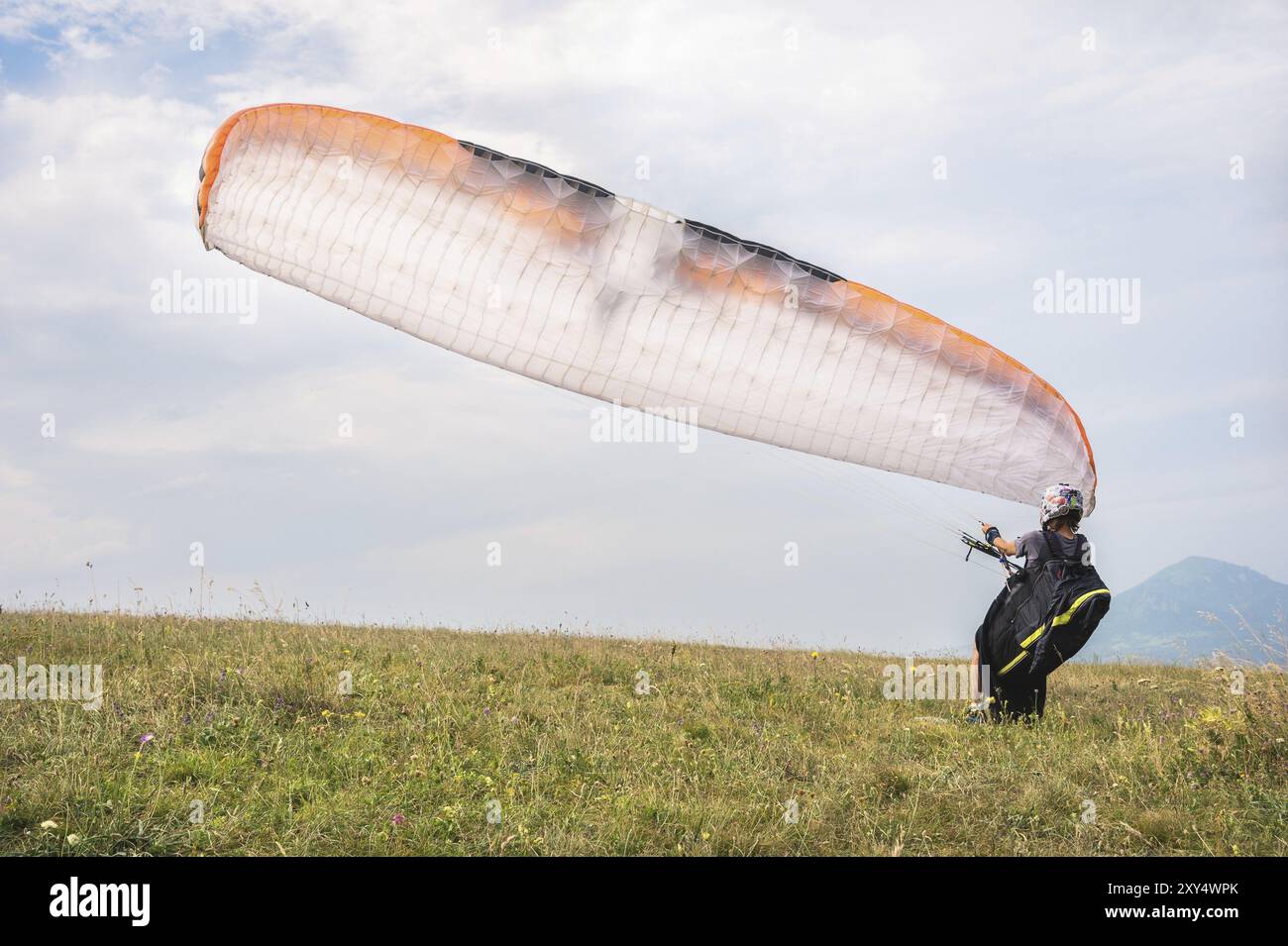 The paraglider opens his parachute before taking off from the mountain ...