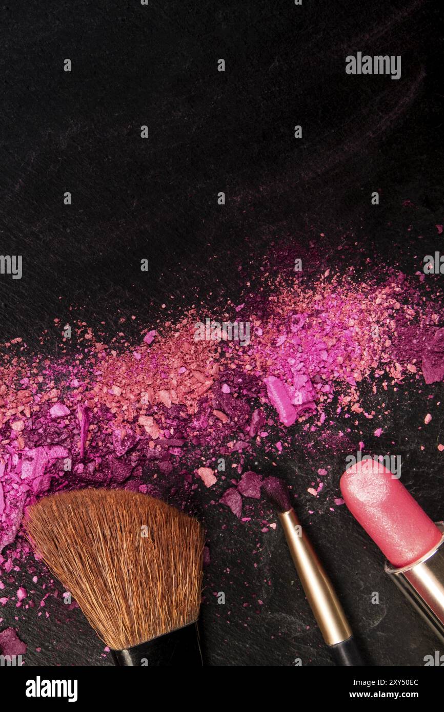 Make-up brushes, lipstick, and crushed cosmetics, overhead shot on a ...