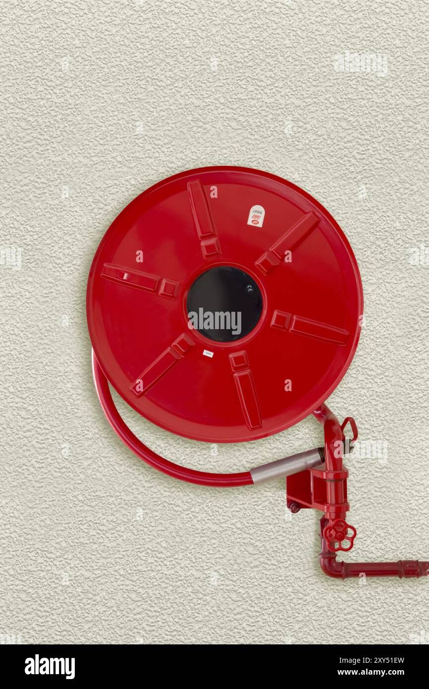 A rolled-up fire hose on a reel in a hallway Stock Photo - Alamy
